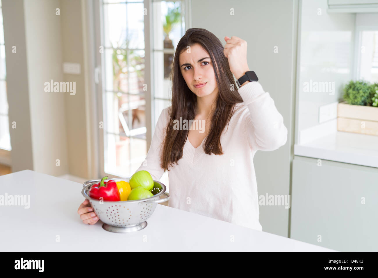 Beautiful young woman using colander to wash and clean vegatables ...