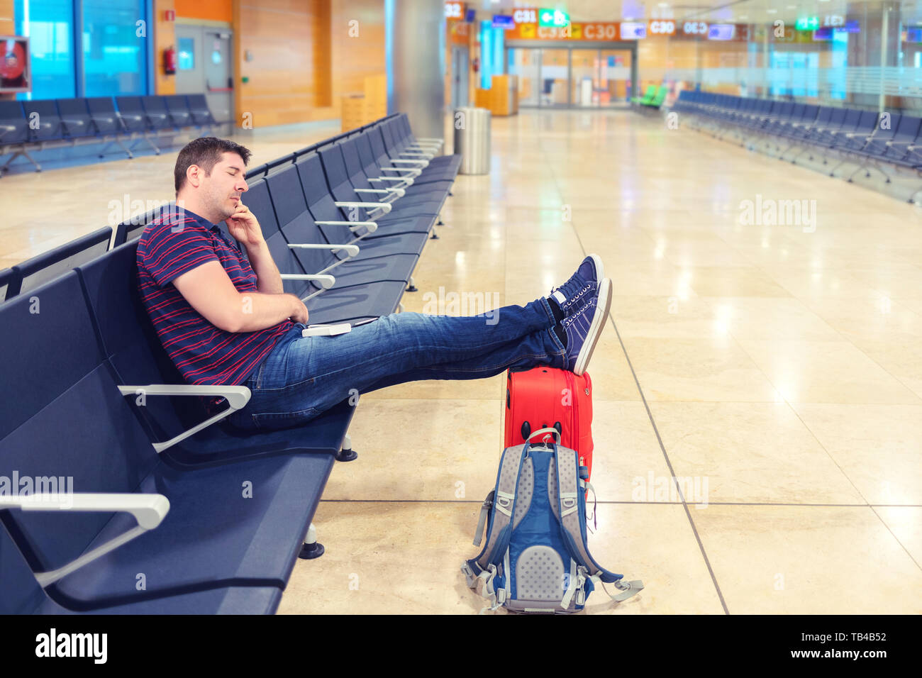 Tired tourist sleeping with legs on suitcase in airport terminal Stock ...