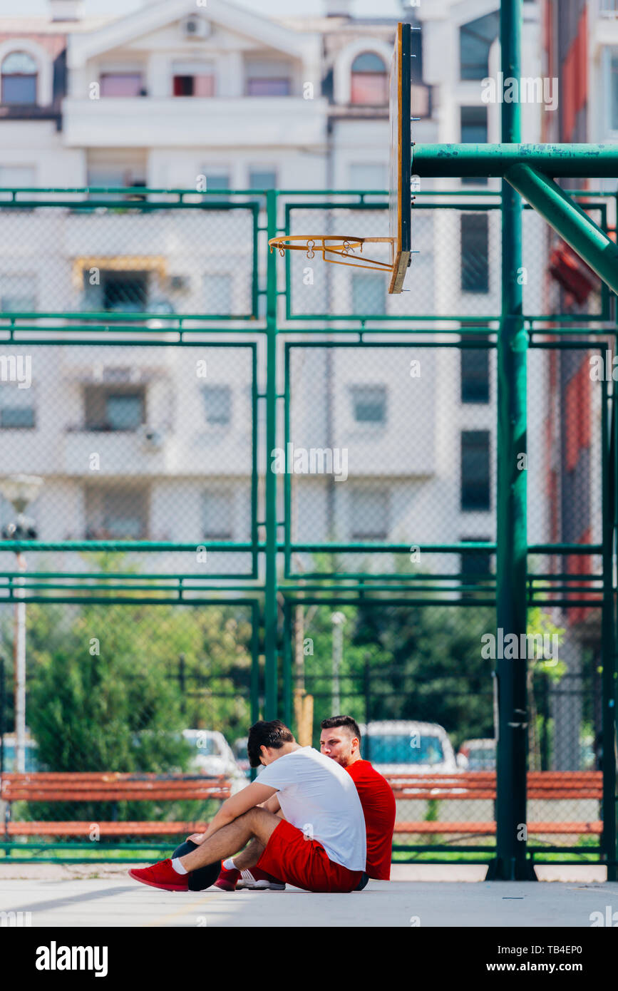 Two friends after a long hard basketball game have some rest on the ...