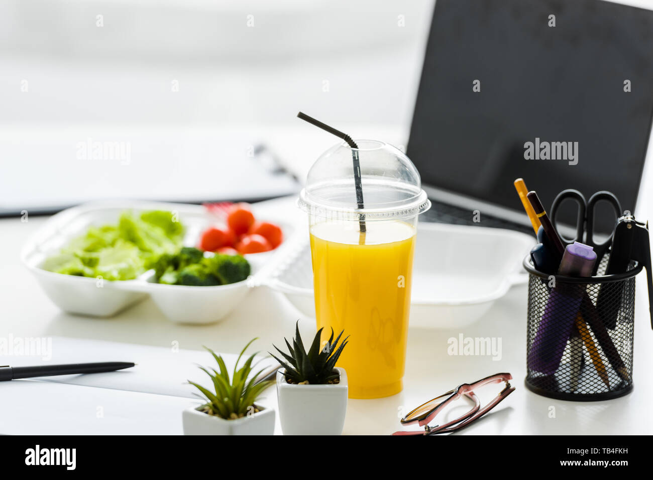 orange juice and green plants near tasty vegetables and laptop with ...