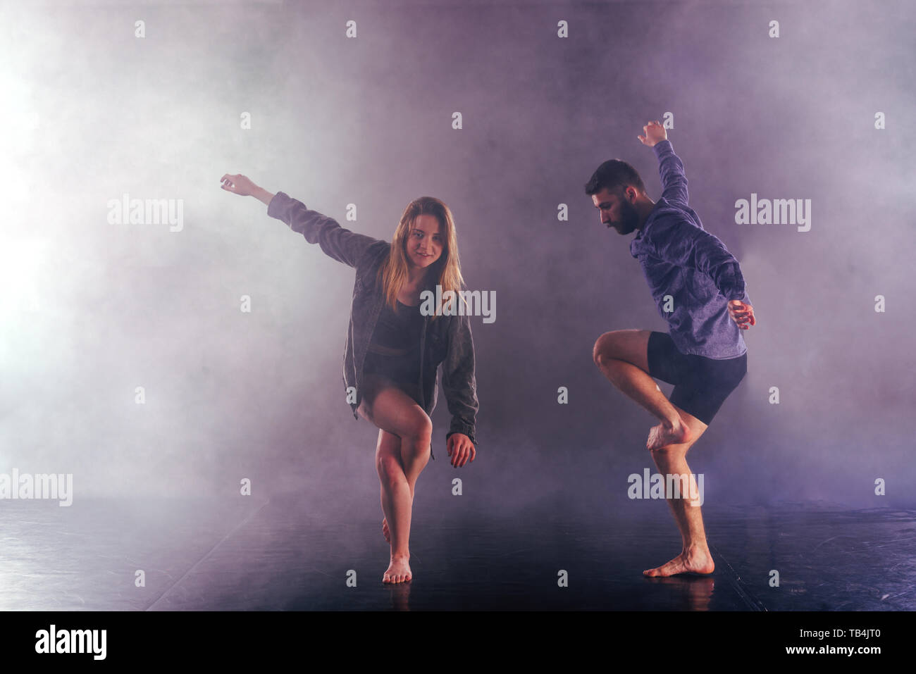Two modern dancers stretching their shoeless feet high in the air ...