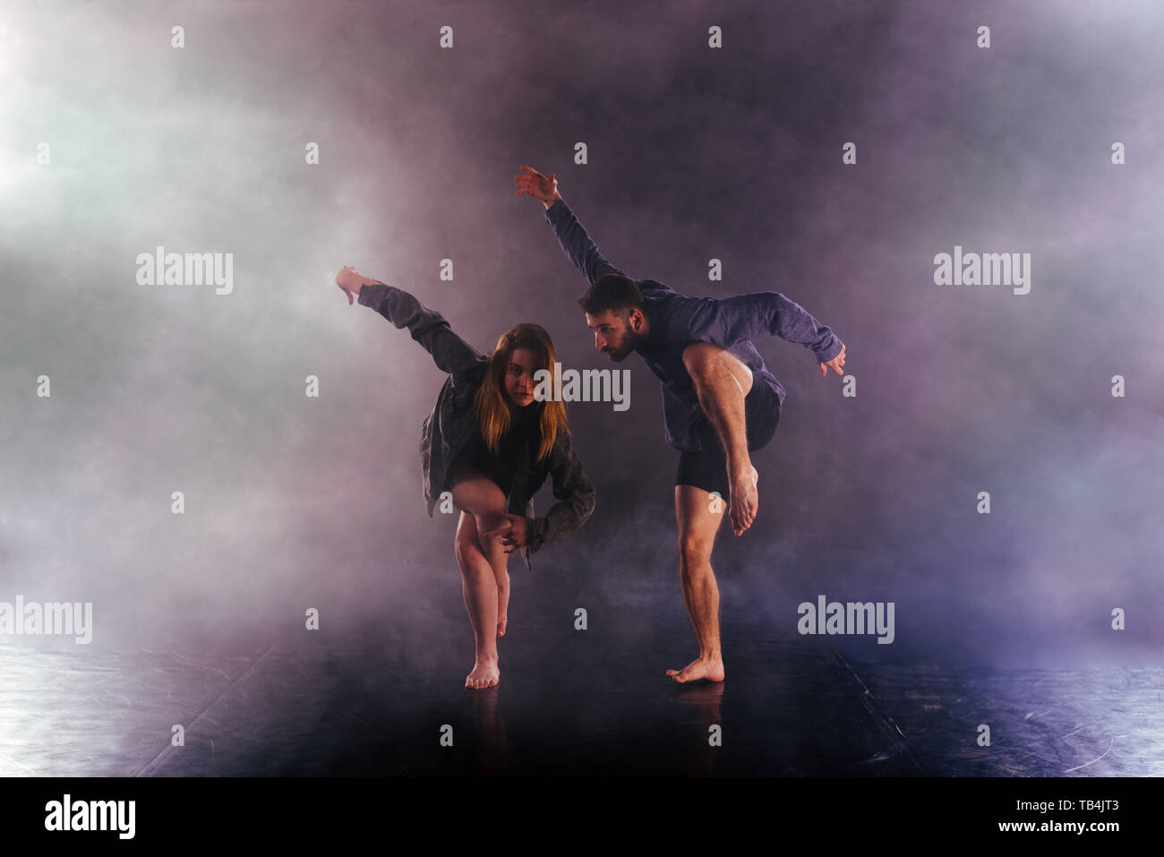Two modern dancers stretching their shoeless feet high in the air ...