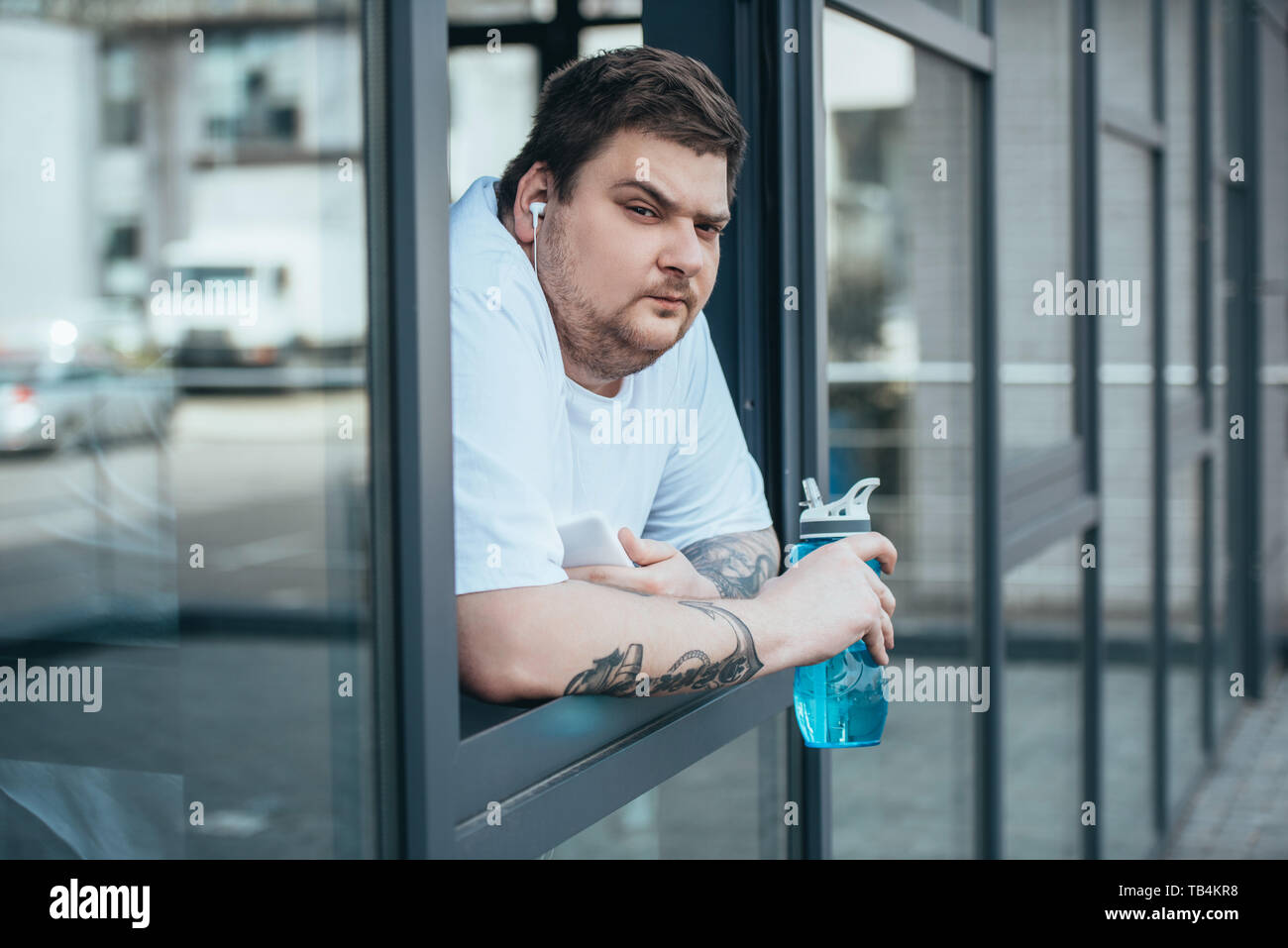 obese man with earphones and smartphone holding sport bottle and ...