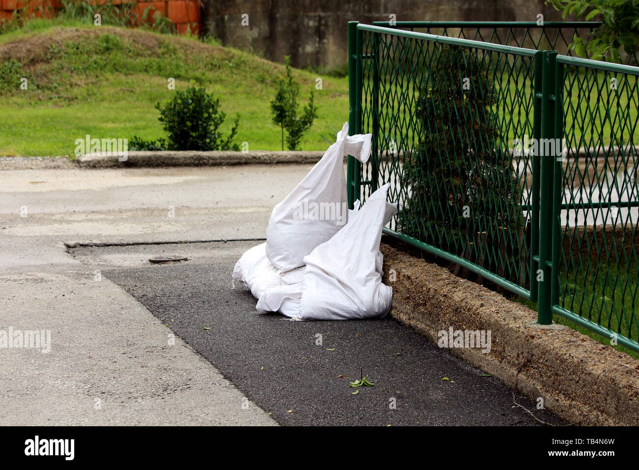 White sandbags loaded with sand left on street corner next to dark ...