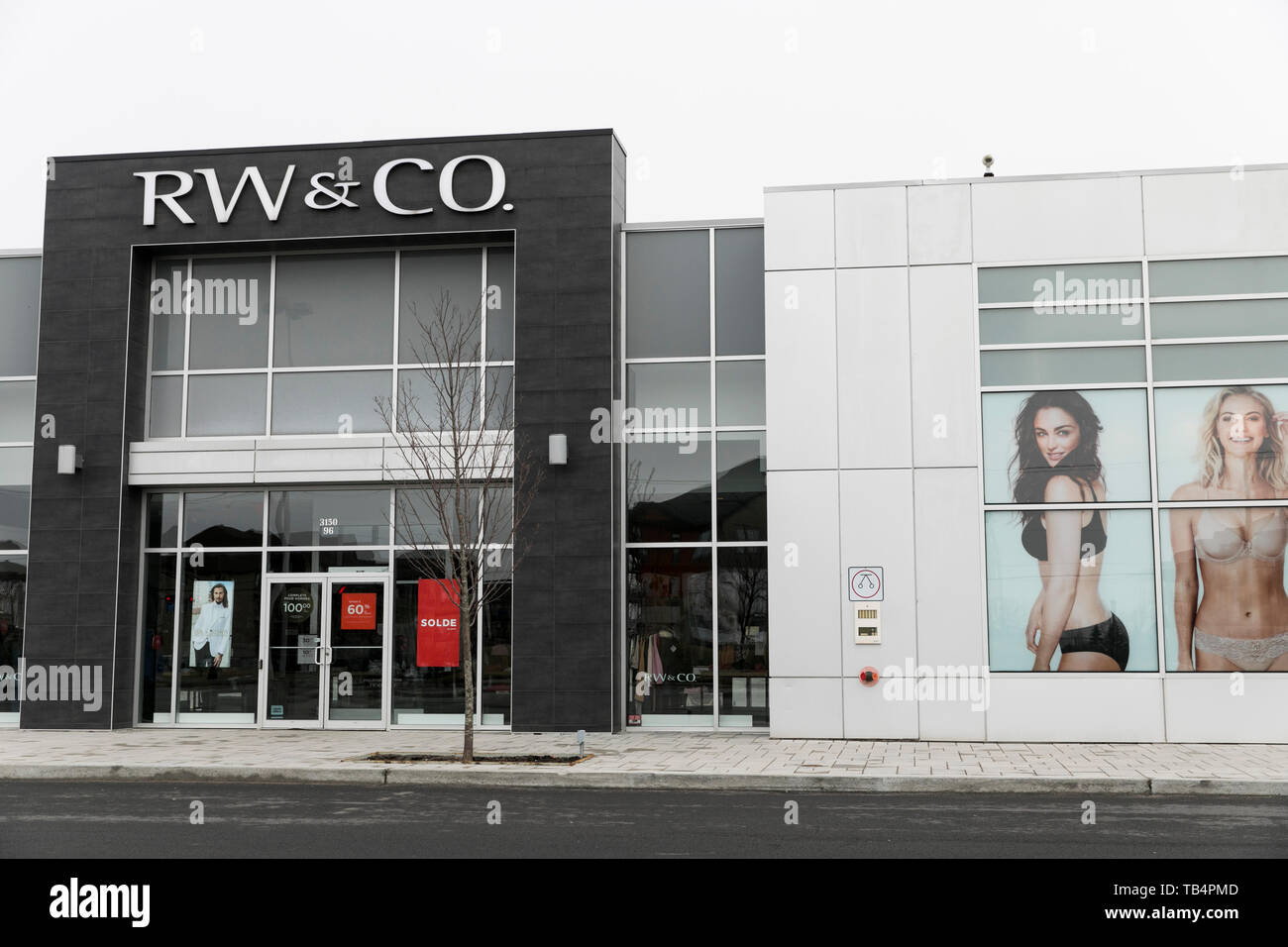 A logo sign outside of a RW&CO retail store location in Vaudreuil ...