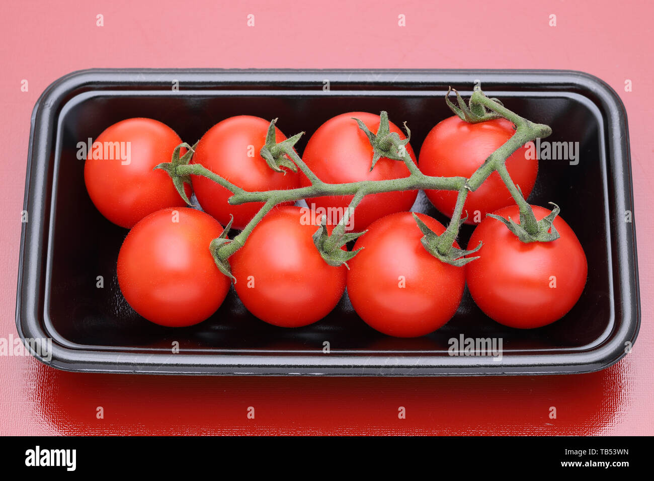branch of cherry tomatoes in a plastic pack, red background Stock Photo ...