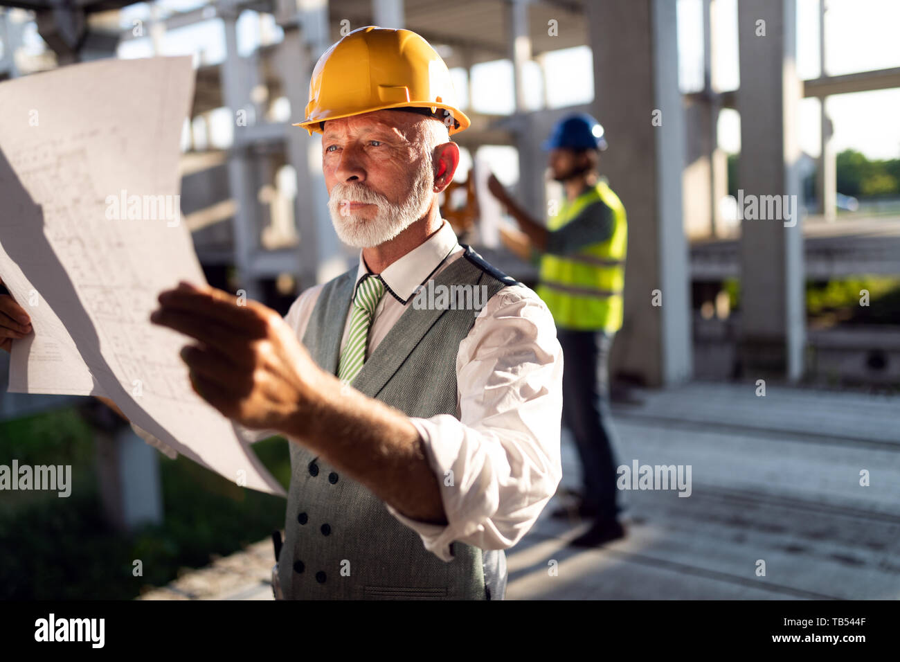 Engineer and building site manager dealing with blueprints and plans ...