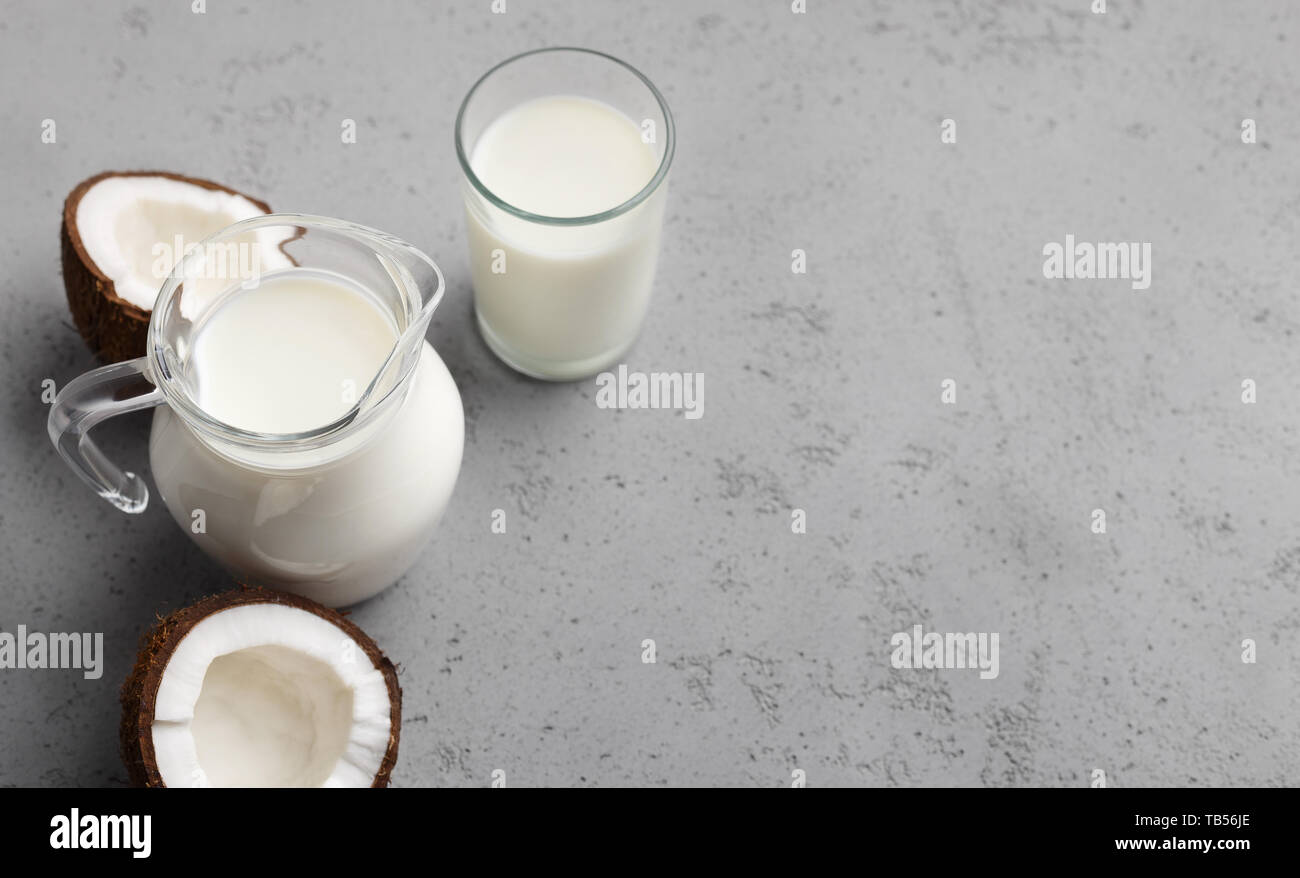 Chopped fresh coconut , jar and glass of coco milk on grey background ...