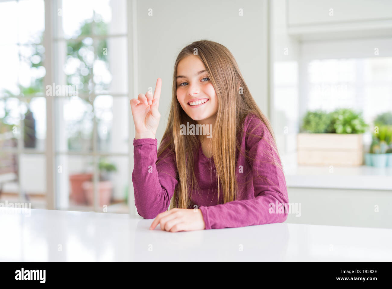 Beautiful young girl kid on white table showing and pointing up with ...