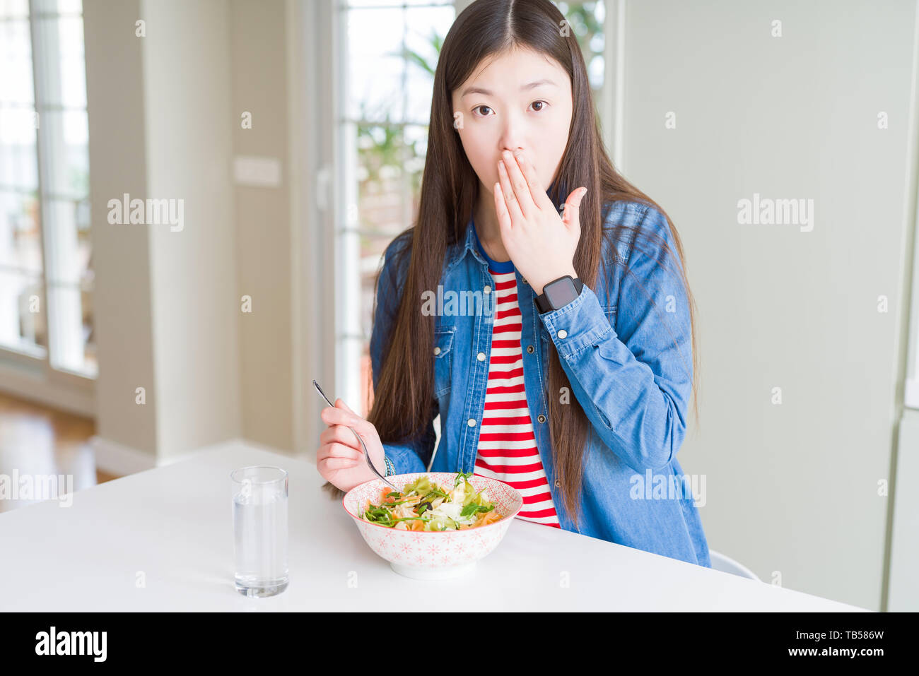 Beautiful Asian woman eating healthy pasta salad cover mouth with hand ...