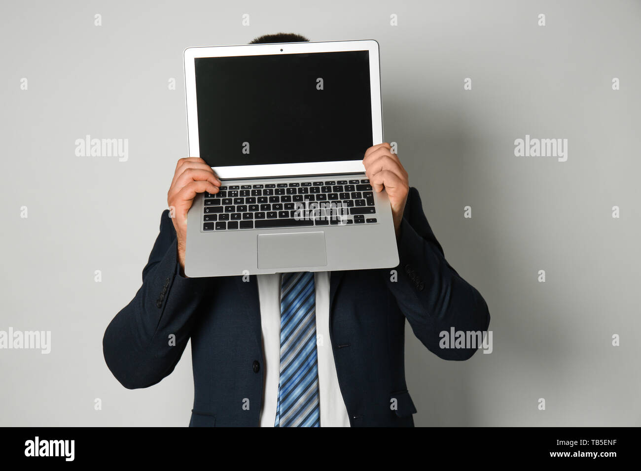 Businessman hiding face behind laptop on light background Stock Photo ...