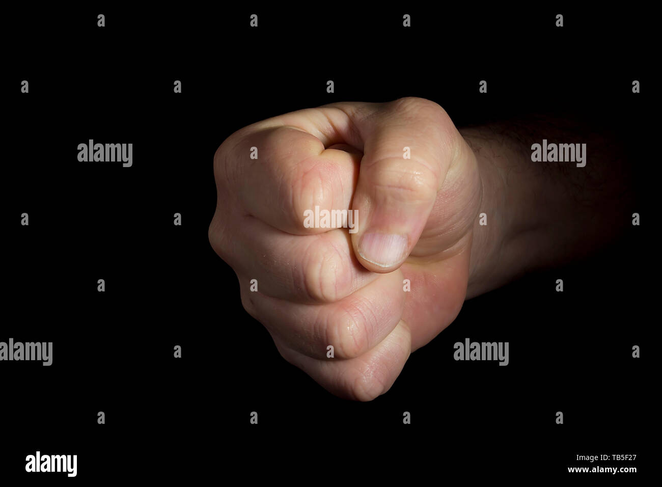 Male hand clenched into a fist on a black background Stock Photo - Alamy