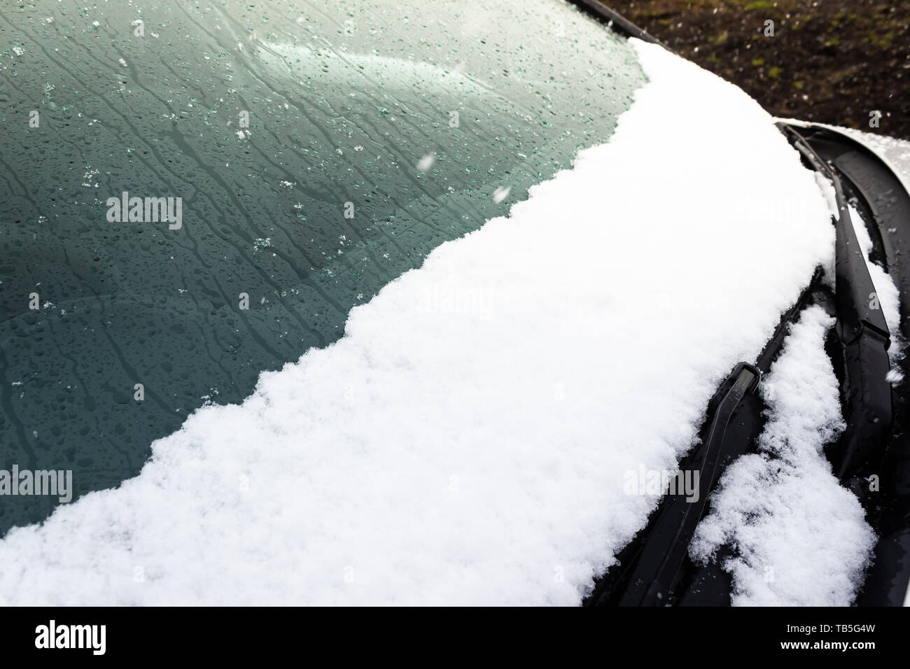 Car windshield and wiper under snow. Snowfall in city, changing weather ...