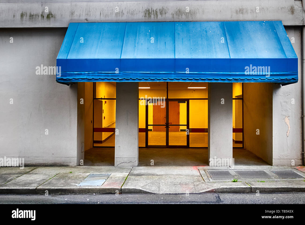 City building entrance with blue awning and yellow light from inside ...