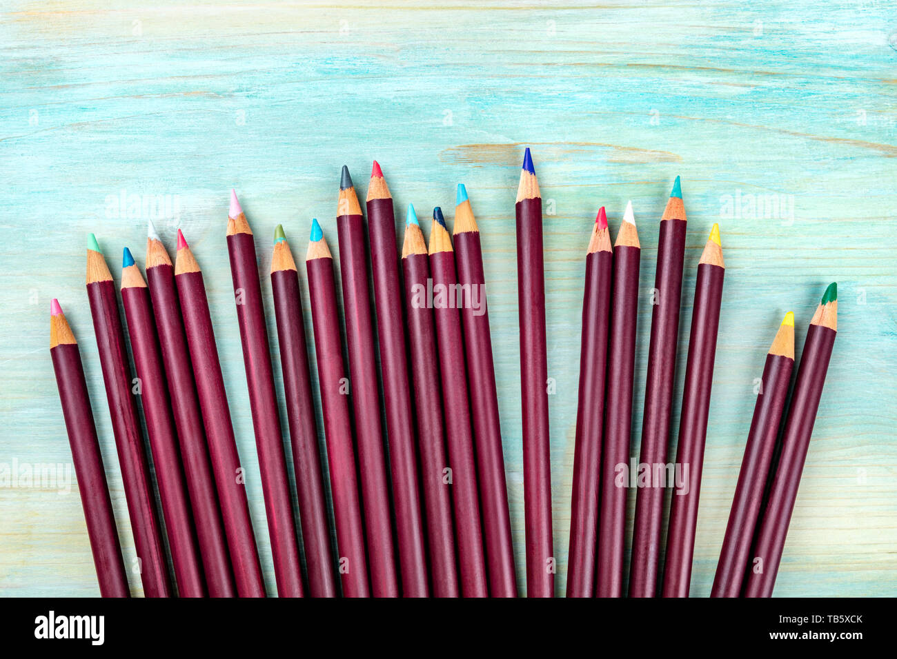 Color pencils, shot from the top on a vibrant teal blue background with ...
