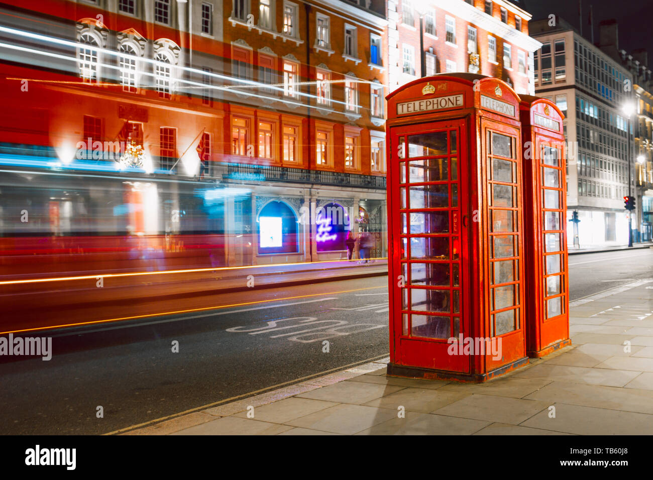 Light trails of a double decker bus next to the iconic telephone booth ...