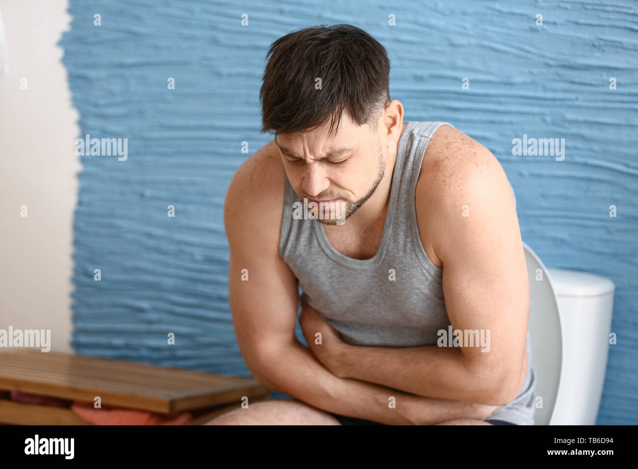 Man suffering from diarrhea while sitting on toilet bowl at home Stock ...