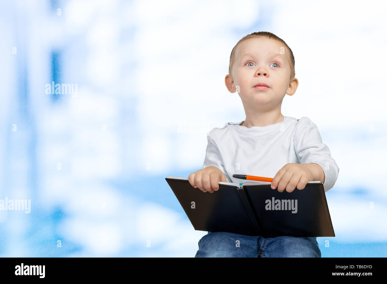 A young school boy is holding a blue book Stock Photo - Alamy