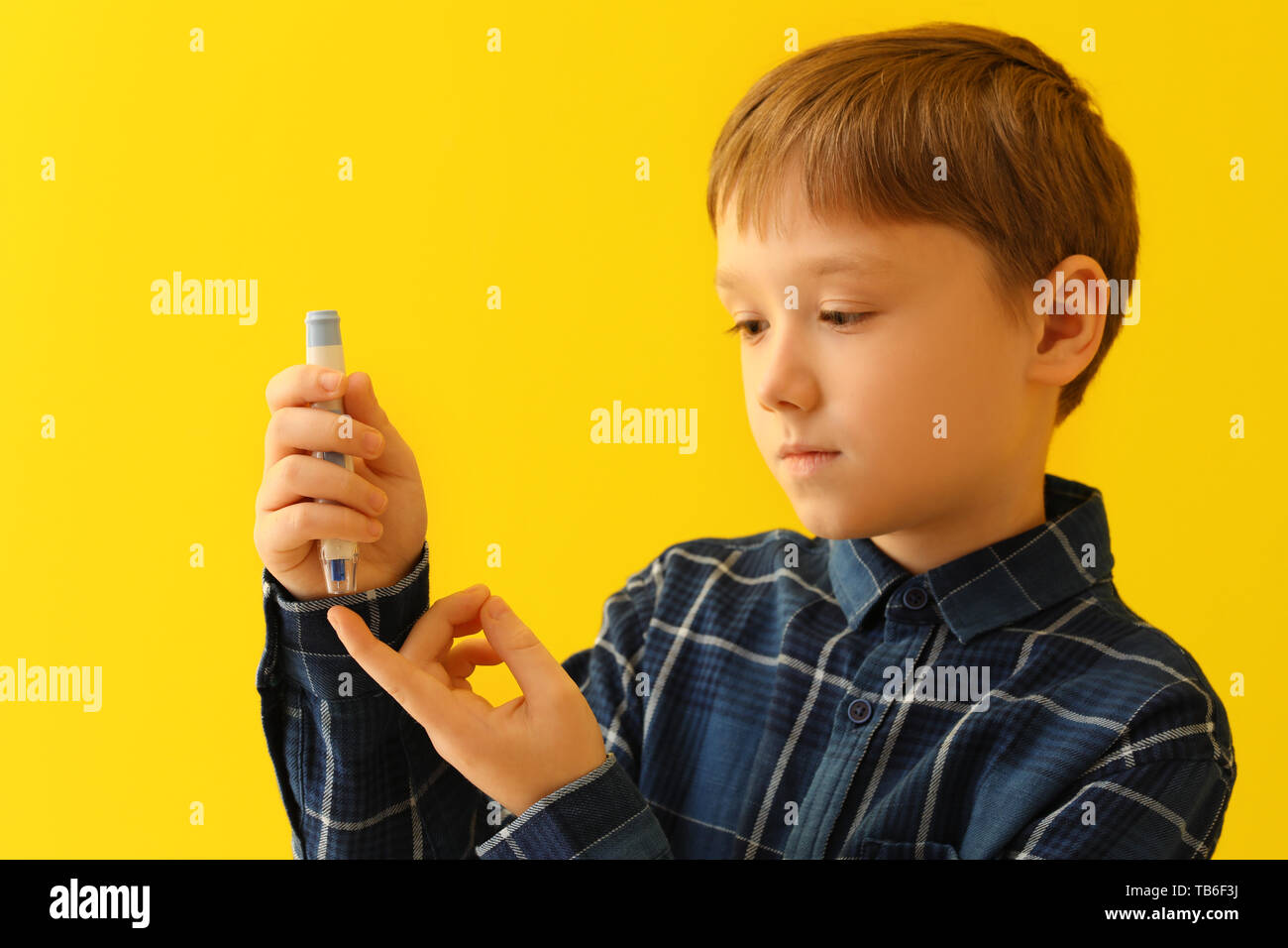 Diabetic child taking blood sample with lancet pen on color background ...