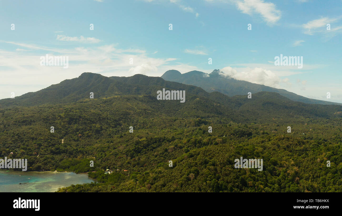 Tropical landscape: Mountains with forest, against blue sea with blue ...