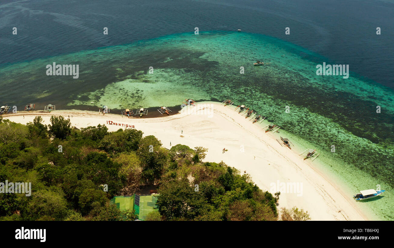 Tropical island and sandy beach surrounded by atoll coral reef and blue ...