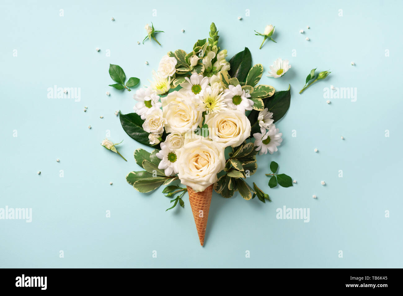 Summer minimal concept. Ice cream cone with white flowers and leaves on ...