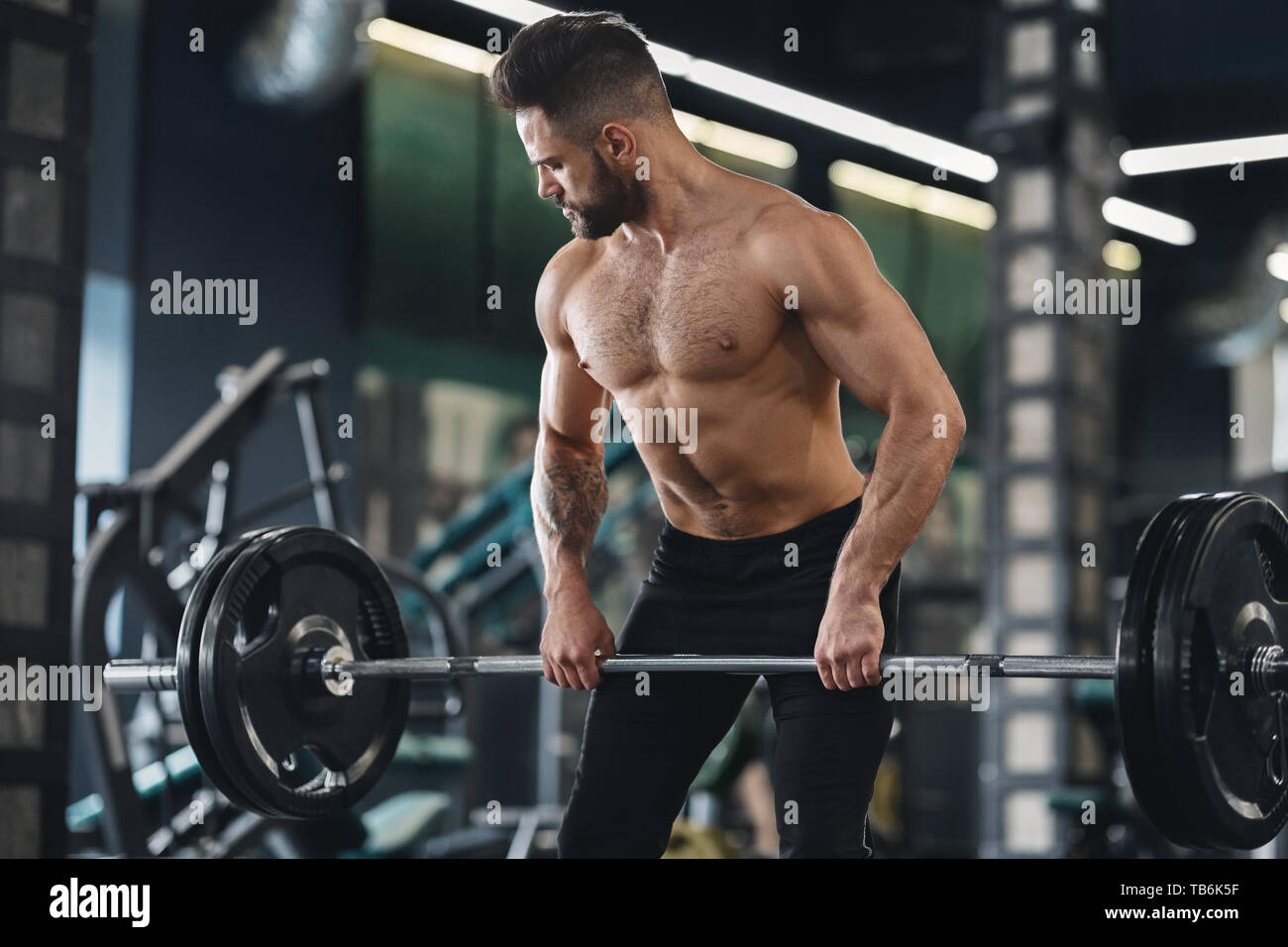 Strong weightlifter working out with heavy barbell in gym, free space ...