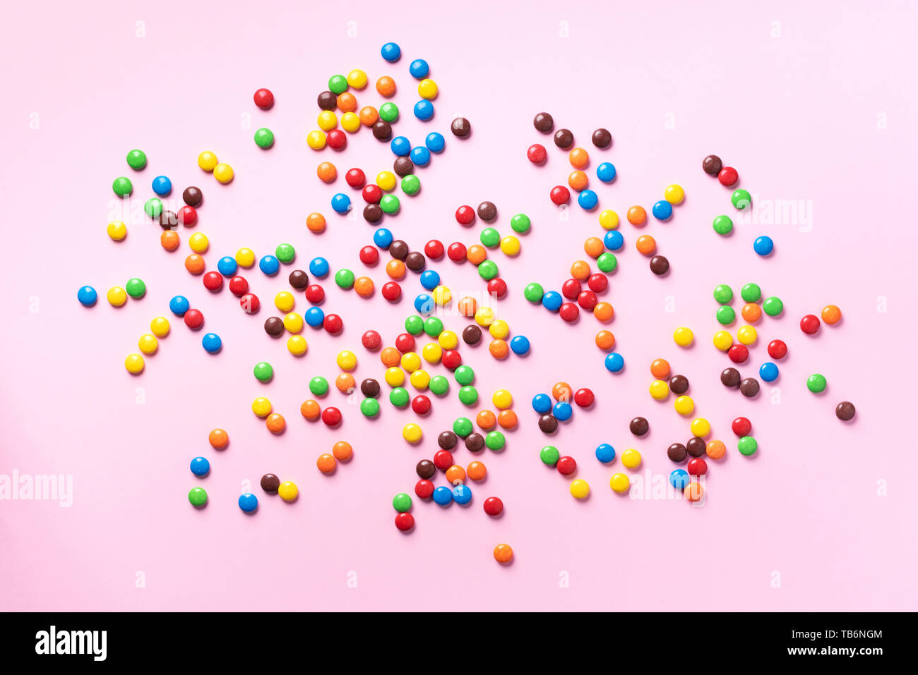 Rainbow colorful candies on pink background. Coated chocolate sweet ...