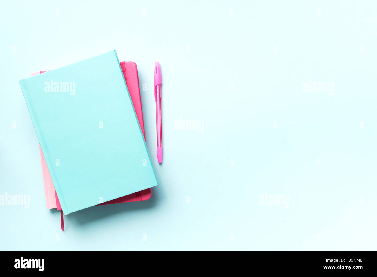 Top view of open pink, turquoise notebooks on pastel blue background ...