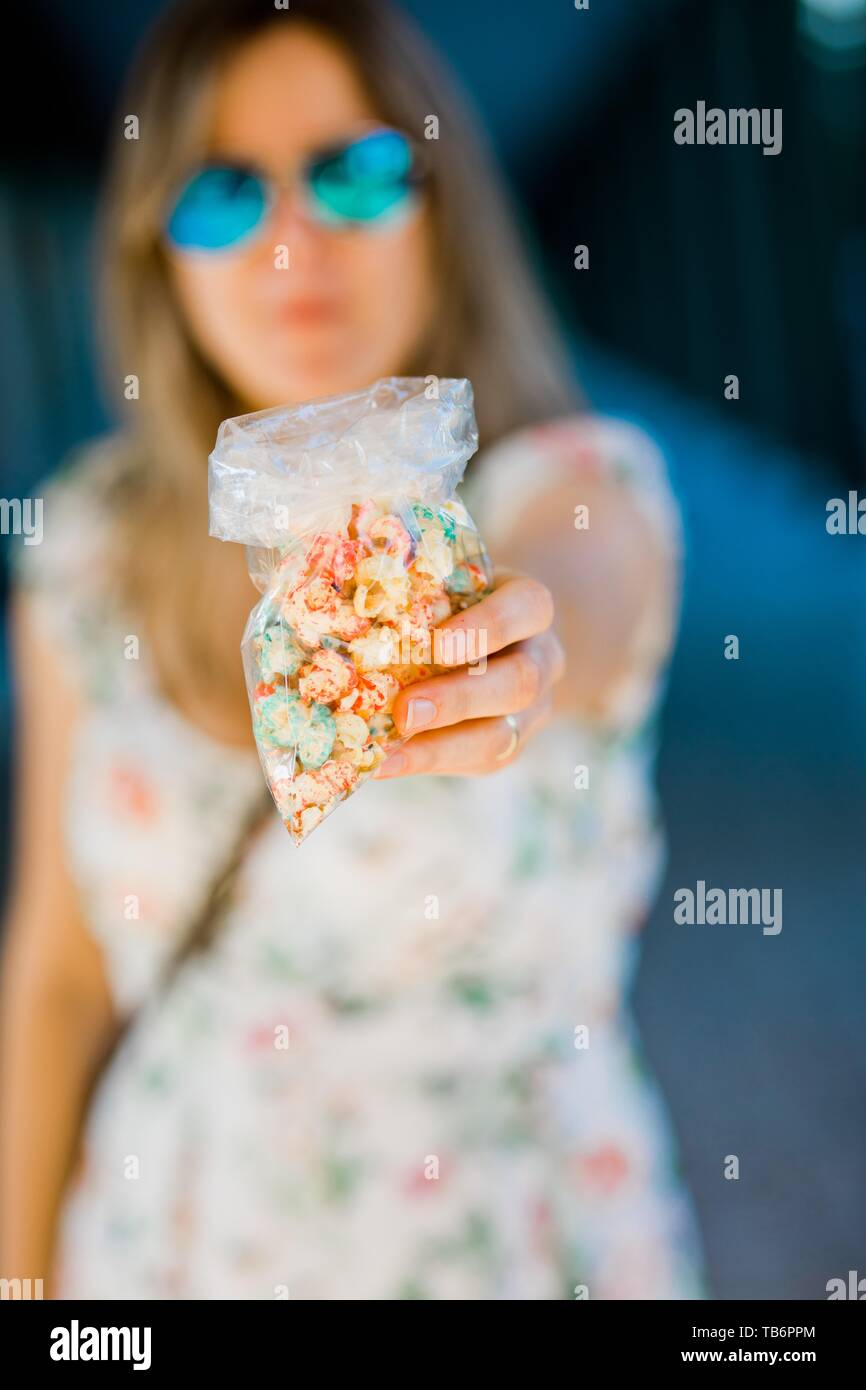 A woman offering sweet popcorn from small plastic bag Stock Photo - Alamy