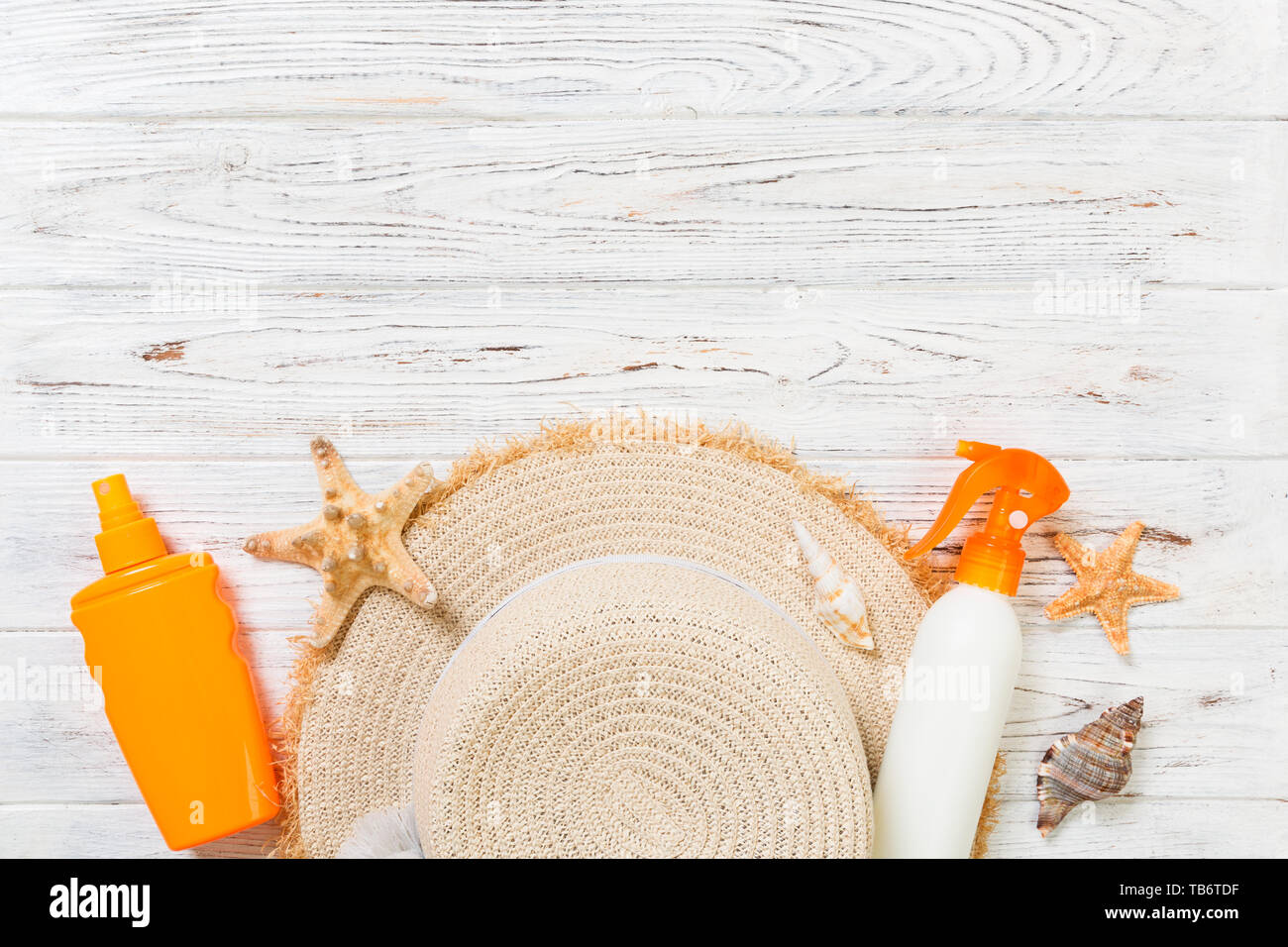 Sunscreen bottles with starfish and sunhat on white wooden table with ...