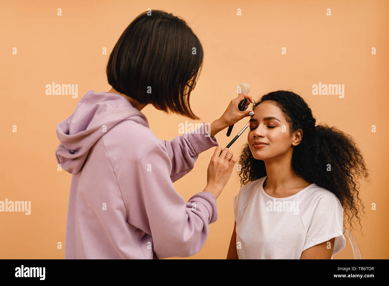 Professional stylist corrects makeup during photo shoot Stock Photo - Alamy