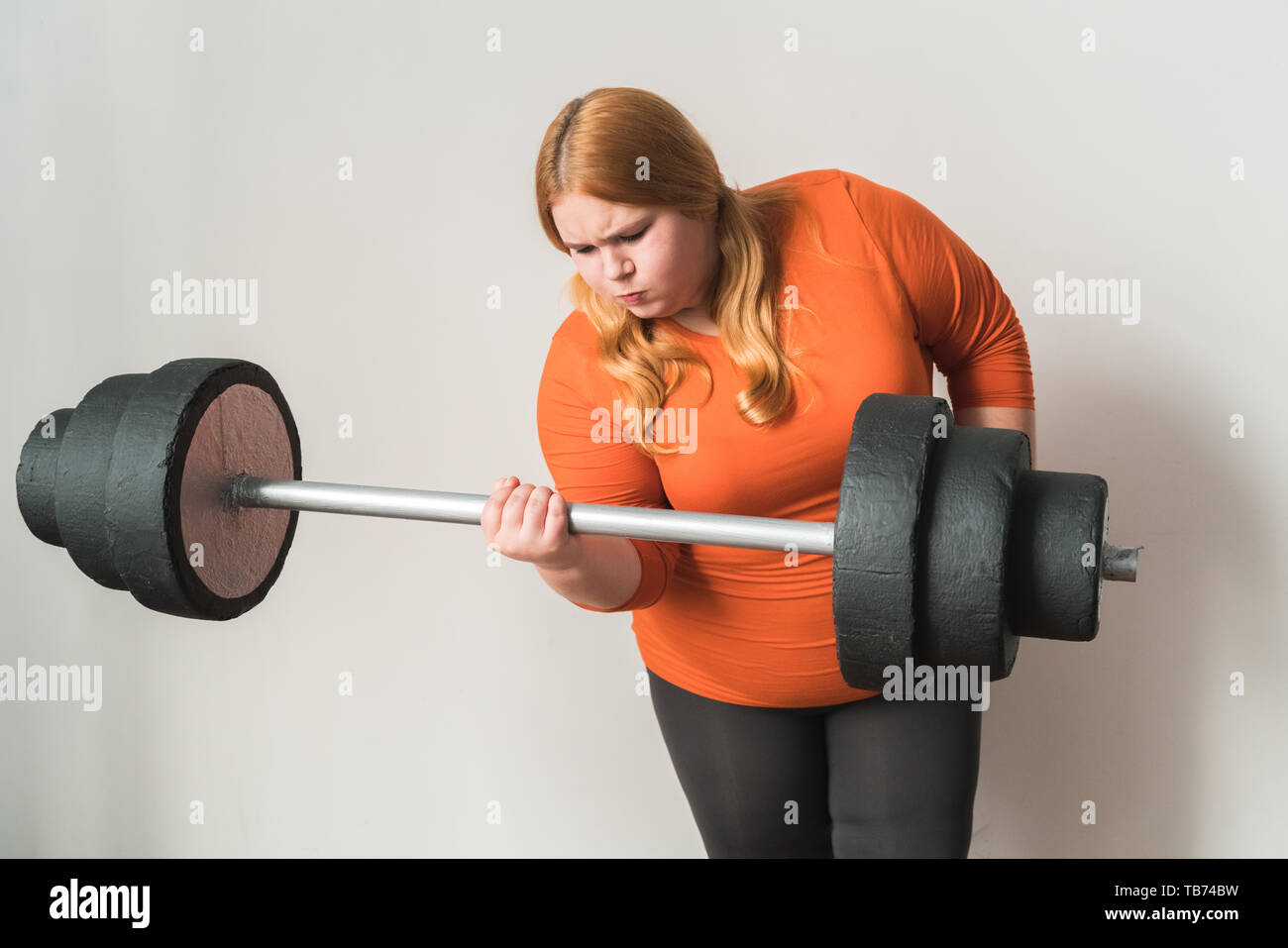 Chubby woman sport at home standing isolated on white wall holding ...
