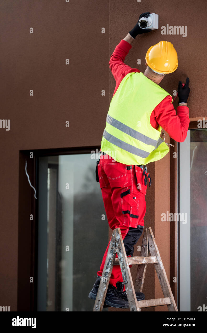 Professional cctv technician working.Technician Fixing Camera On Wall ...