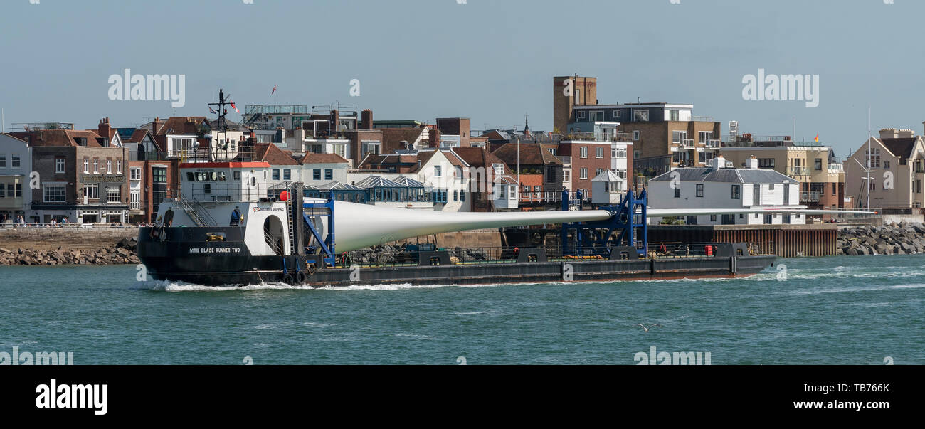 Portsmouth, England, UK. A deck cargo ship with a large wind turbine ...