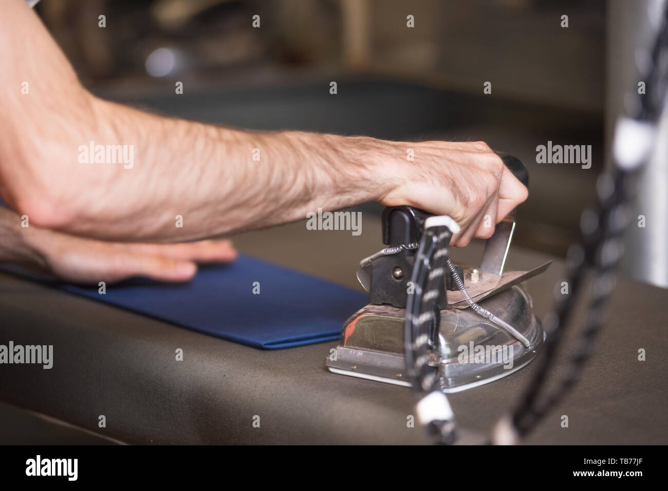 Close up of unrecognizable tailor ironing clothes with old fashioned ...