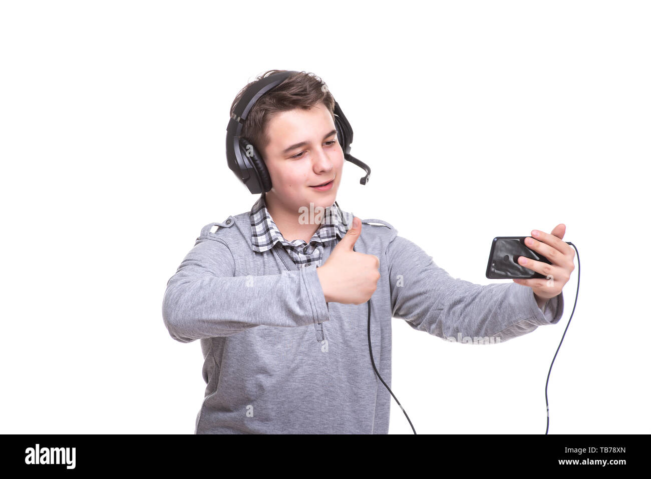 Schoolboy guy with headphones playing on mobile phone. Teenager happy ...