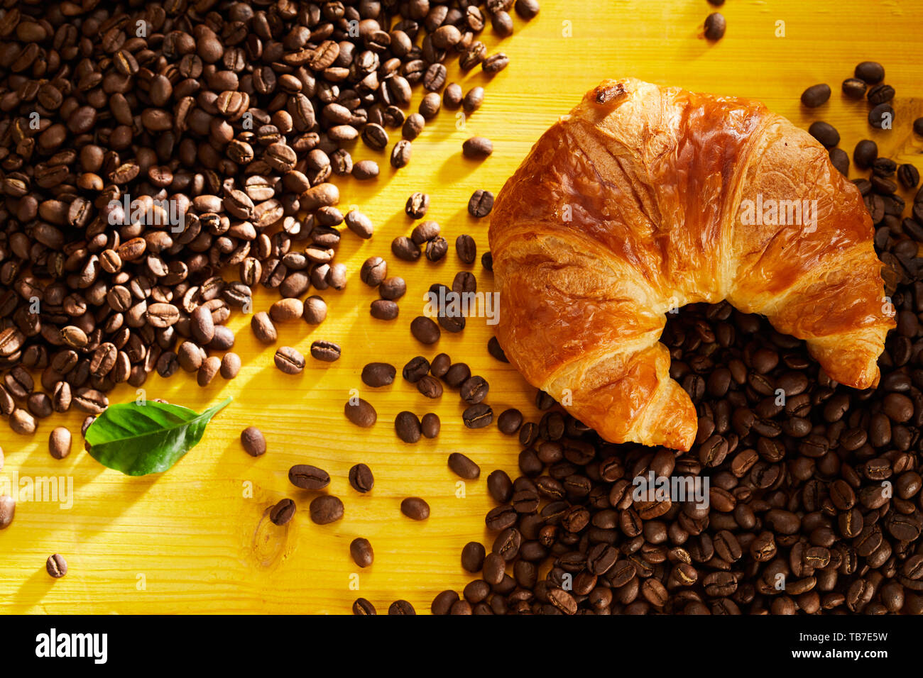 Fresh flaky croissant on roasted coffee beans conceptual of a ...