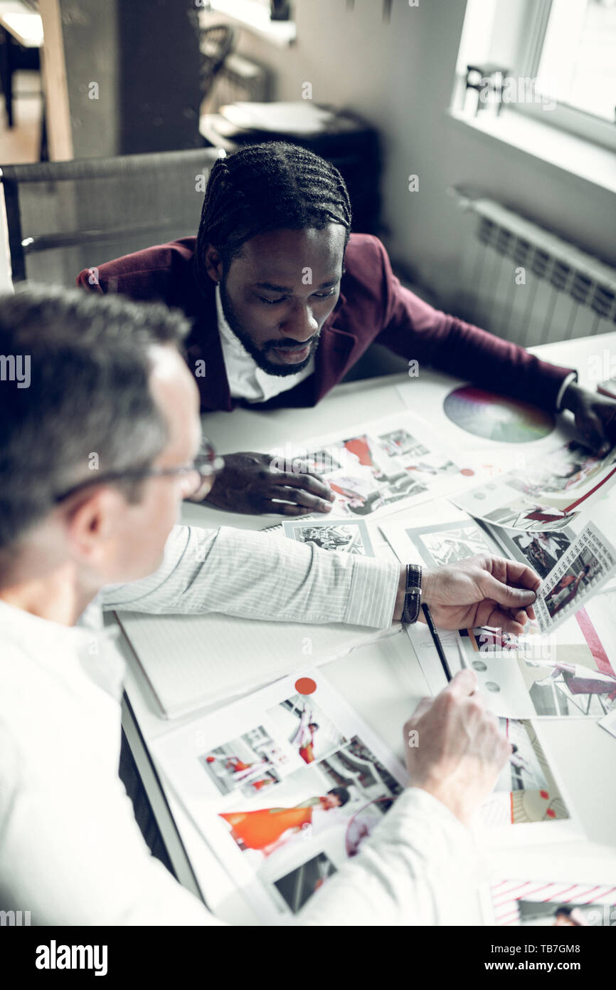 Male fashion designers looking at the photos of models Stock Photo - Alamy