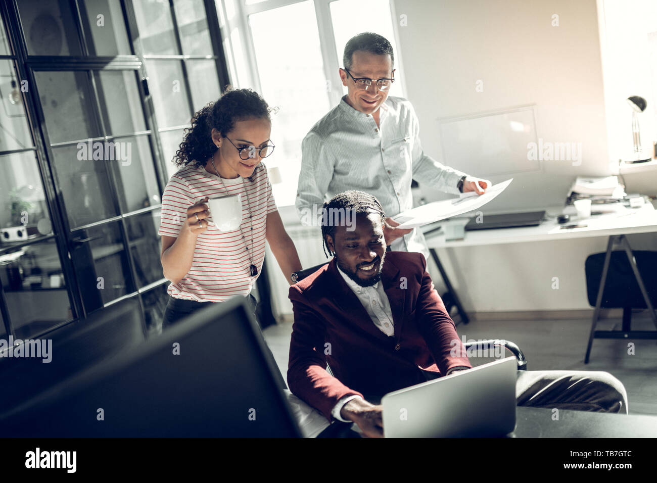 Company of freelancers smiling while working together Stock Photo - Alamy
