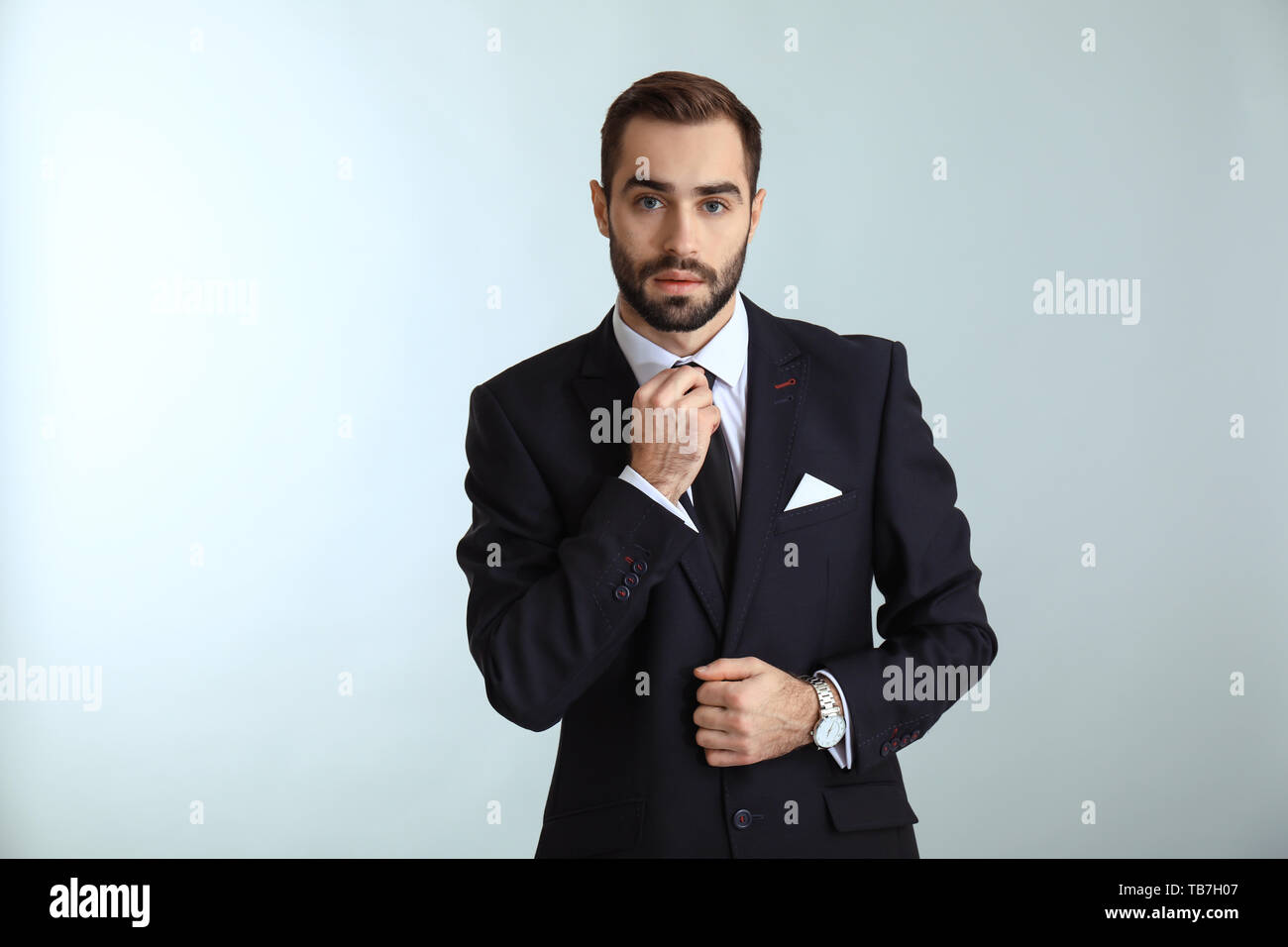 Handsome fashionable man in formal clothes against light background ...