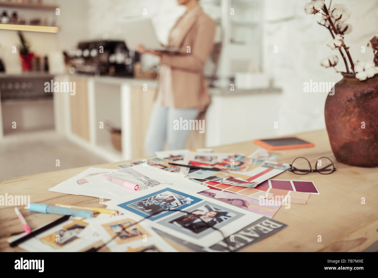 Creative chaos. Woman with a laptop standing behind the table full of ...