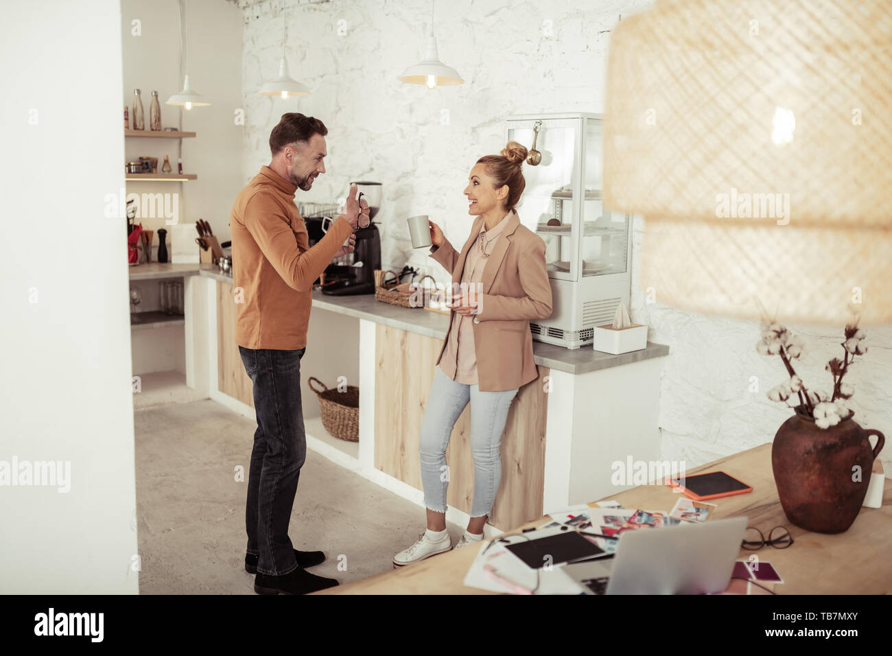 Fooling around. Handsome man standing in the kitchen and telling ...