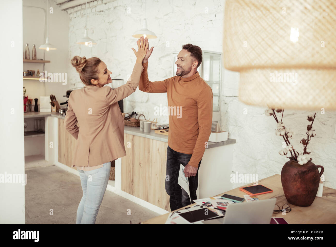 Friendly atmosphere. Two happy colleagues smiling and high-fiving each ...