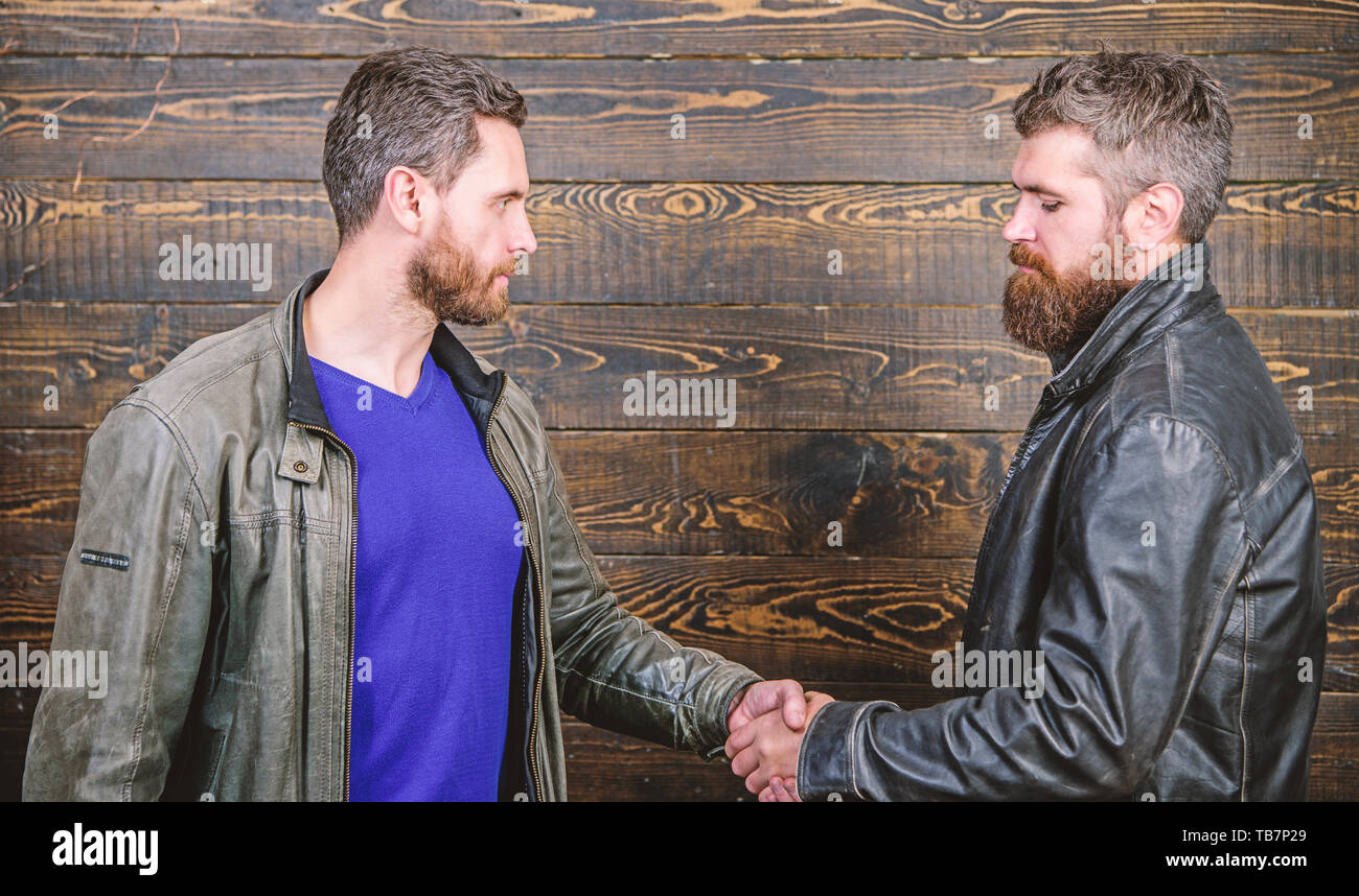 Brutal bearded men wear leather jackets shaking hands. Friendship of ...