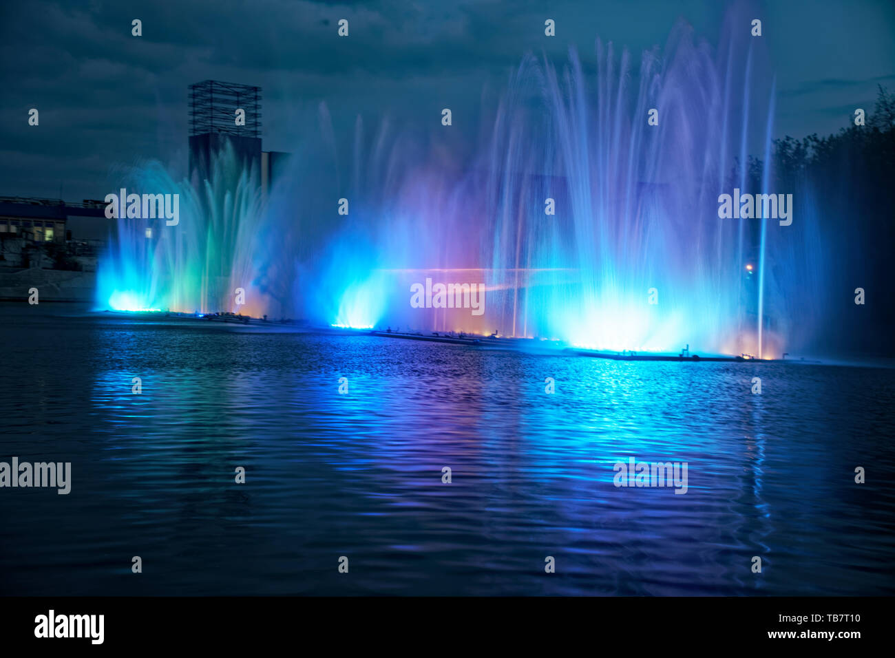 Colorful water fountains with laser and light reflection over lake ...