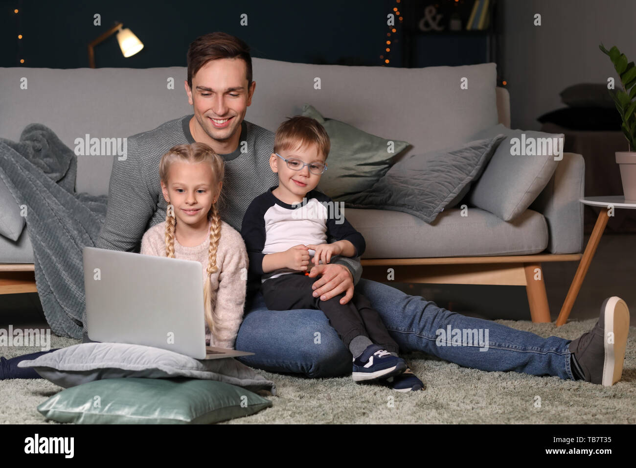 Young father with little children watching cartoons at home Stock Photo ...
