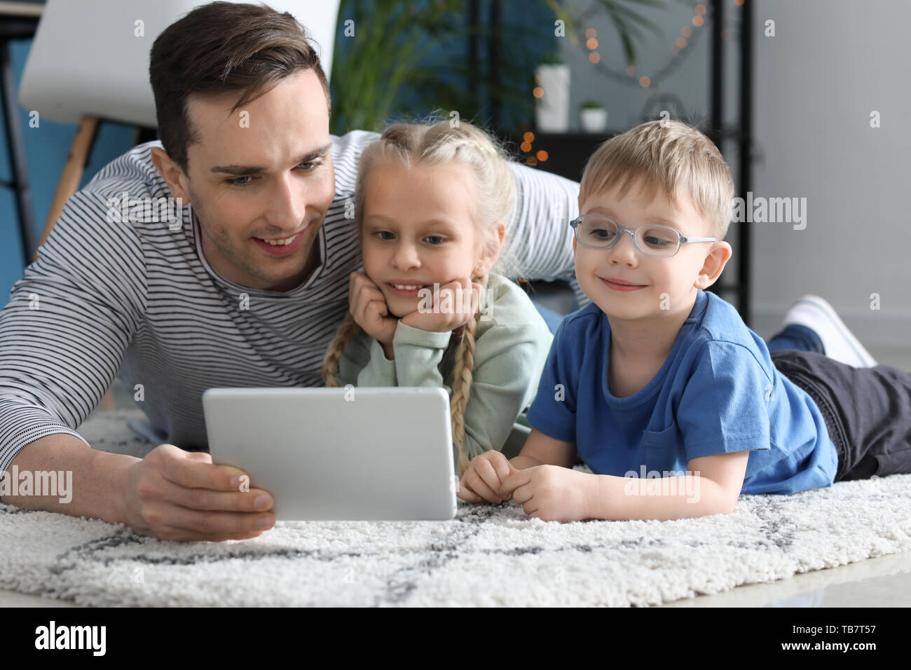 Young father with little children watching cartoons at home Stock Photo ...