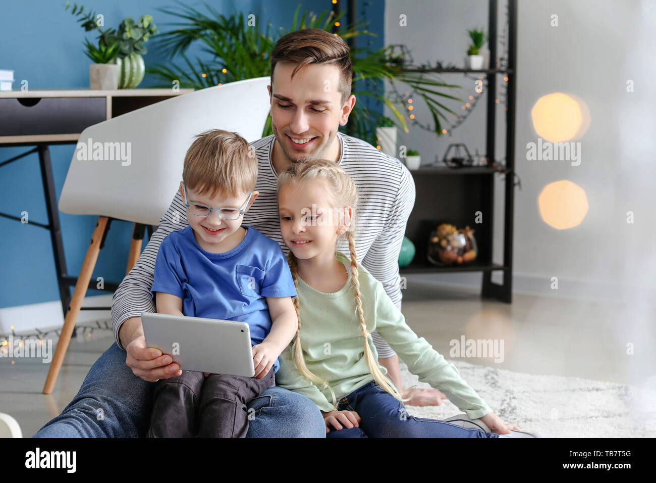 Young father with little children watching cartoons at home Stock Photo ...