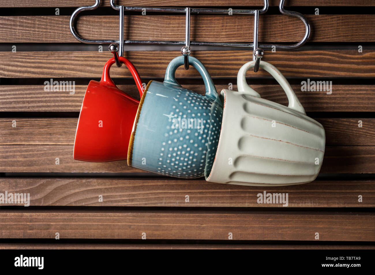 Different tea cups hanging on wooden wall Stock Photo - Alamy